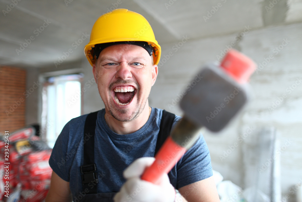 Portrait of screaming male holding big sturdy construction tool. Scary ...