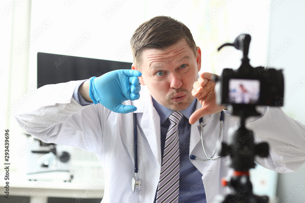 Male vlogger doctor look at camera aganist hospital office background ...