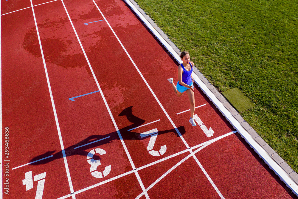 Aerial view of a running young female, athlete on a tartan track ...