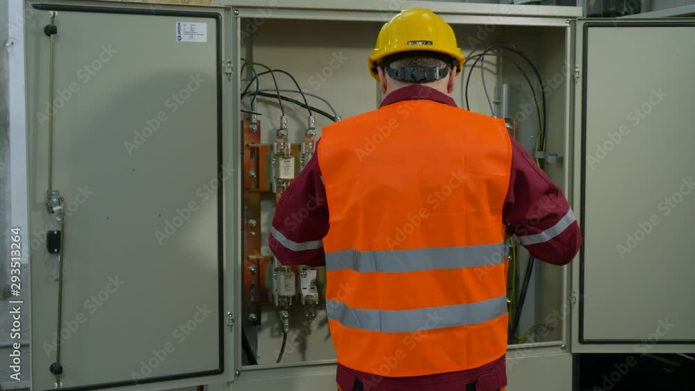 An electrician wearing protective clothes and checking the current ...