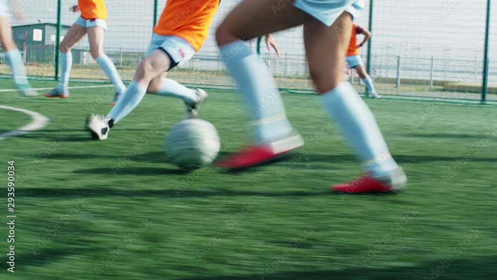 Low section shot of female soccer player dribbling ball on field and ...