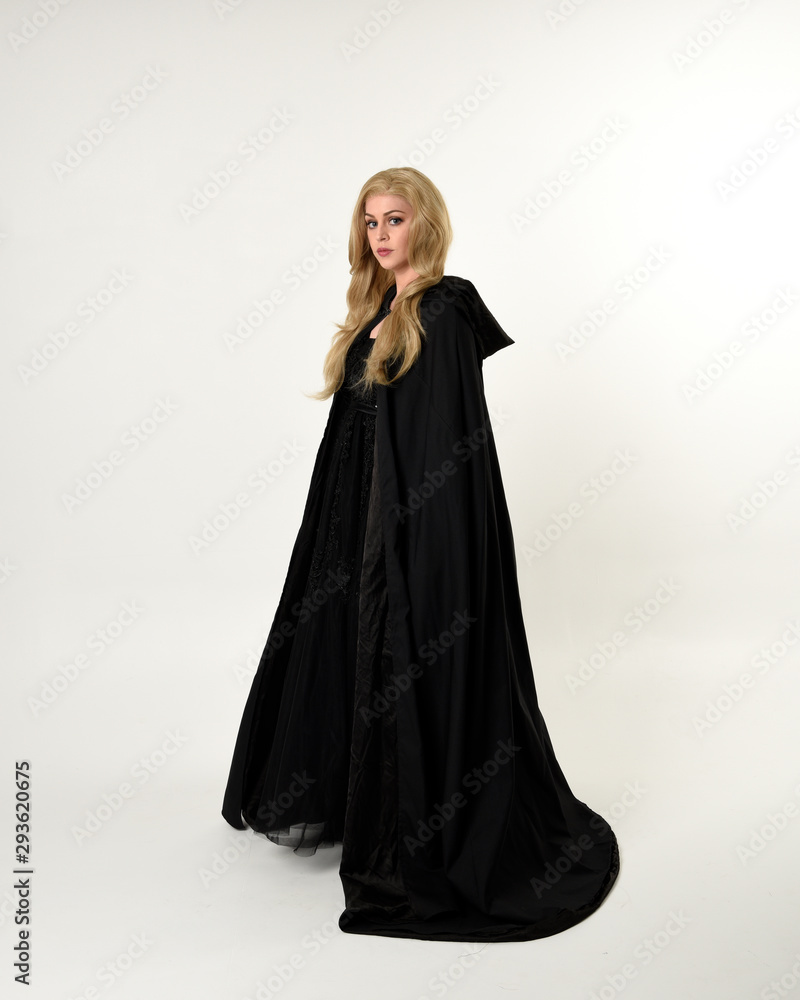 full length portrait of blonde girl wearing long black flowing cloak ...