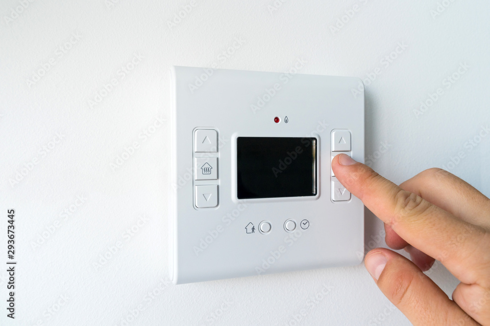 Man hand setting the room temperature on a modern programmable ...
