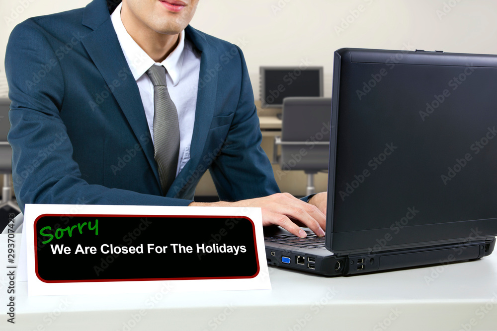 Businessman on a desk with a closed sign using a computer to type a ...