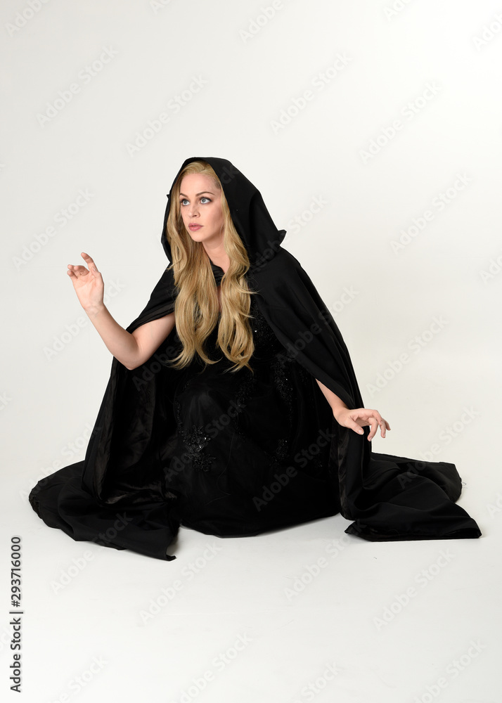 full length portrait of blonde girl wearing long black flowing cloak ...