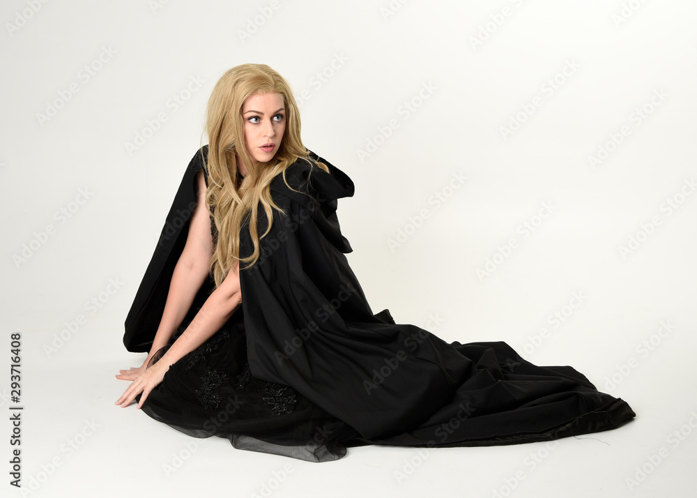 full length portrait of blonde girl wearing long black flowing cloak ...