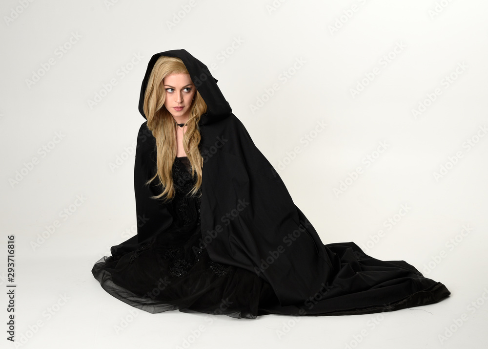 full length portrait of blonde girl wearing long black flowing cloak ...