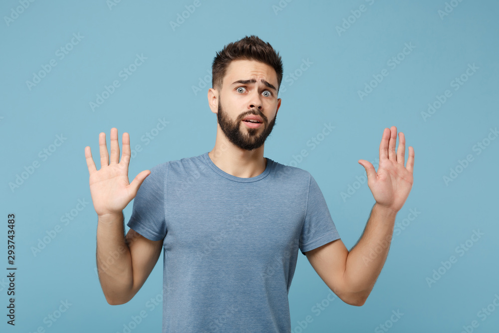 Young shocked scared man in casual clothes posing isolated on blue wall ...