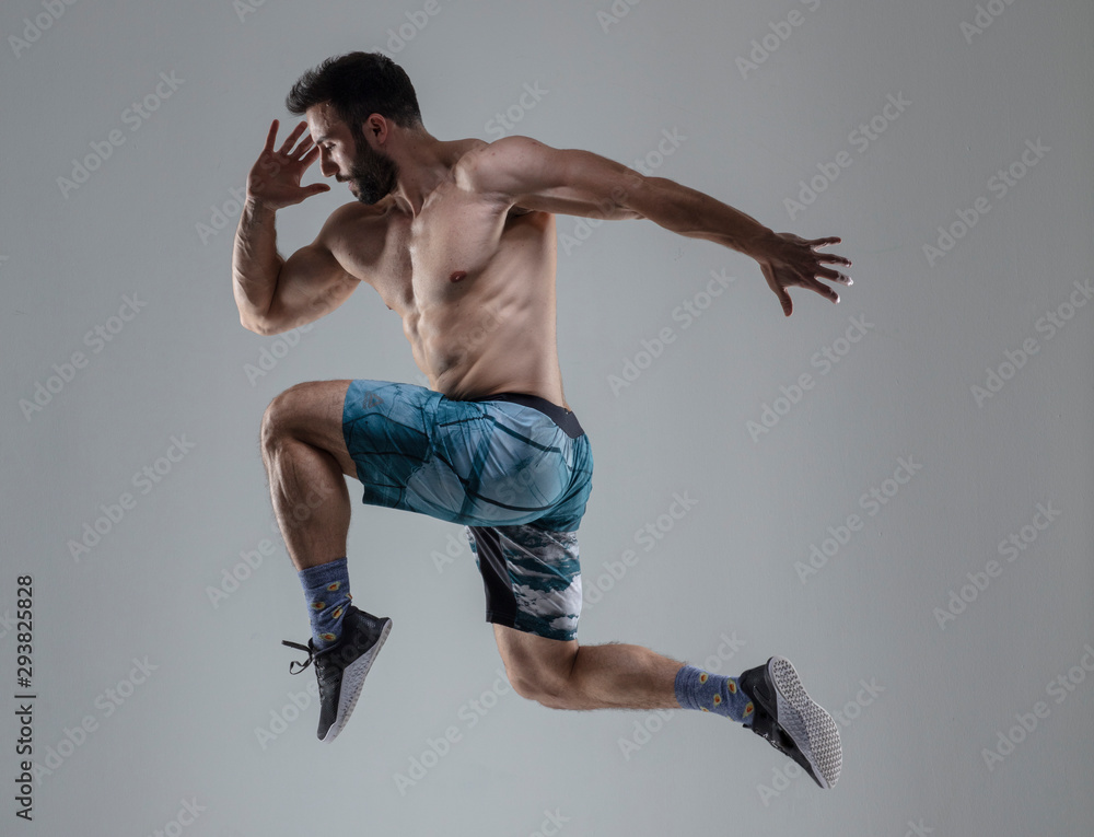 Young athlete is jumping and posing on isolated grey background. Young ...