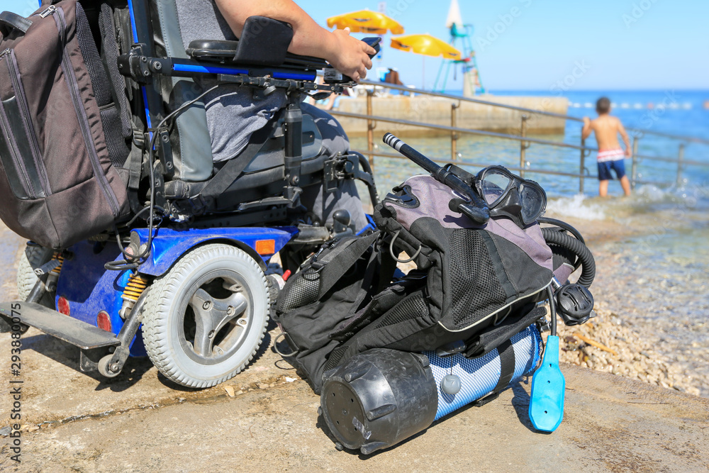 Handicapped disabled scuba diver with equipment on a beach shore ...