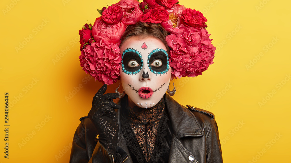 Horrified woman with painted skull on face, dressed in special costume ...