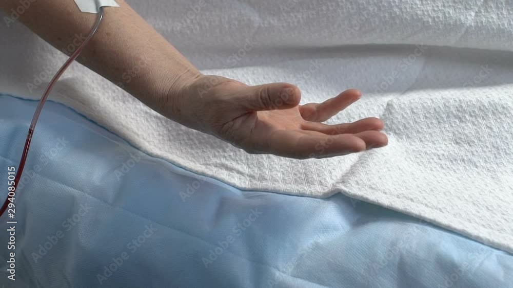 Hand of helpless patient lying on hospital bed, dropper in arm, person ...