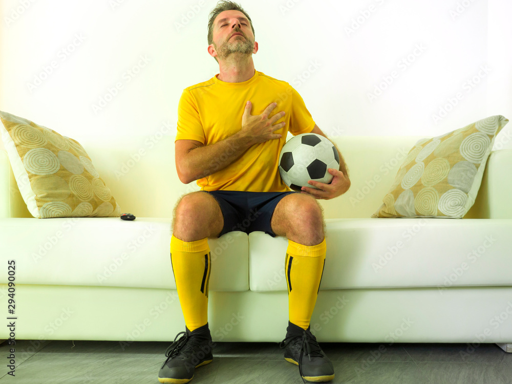 funny portrait of young man in football team uniform watching soccer ...