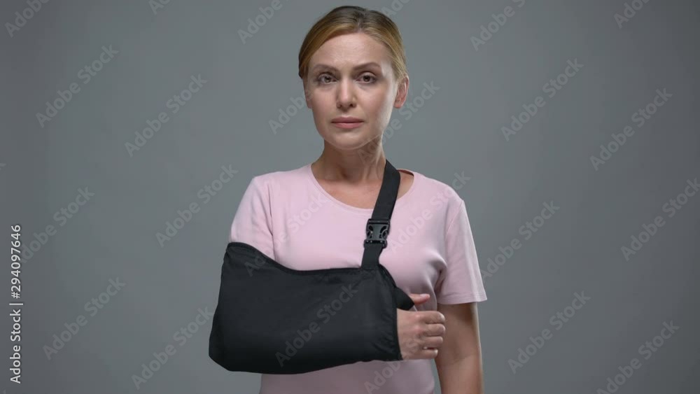 Upset woman with arm sling looking into camera, fracture or sprain ...
