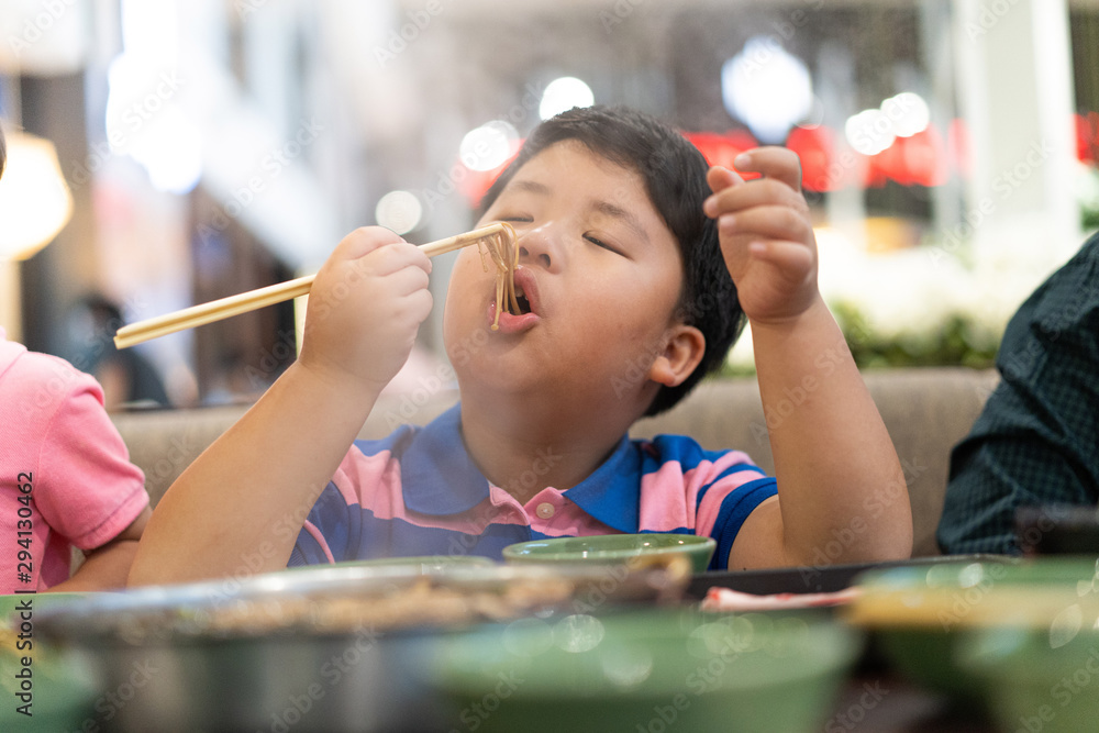 A kid is eating deliciously boiled golden needle mushroom with sukiyaki ...