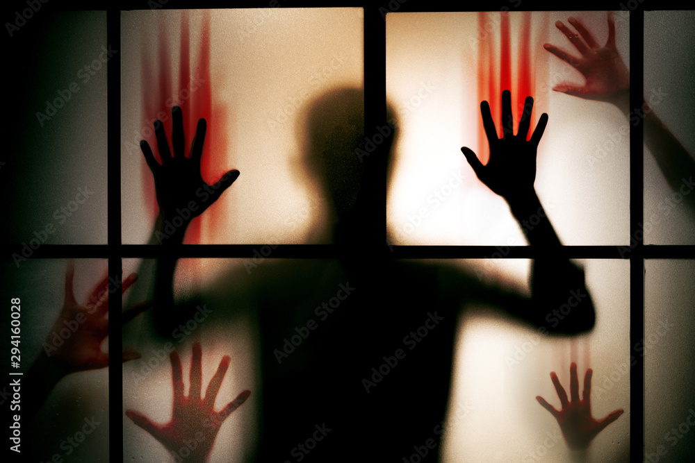 silhouette scared man with red bloody hands stand behind glass door ...