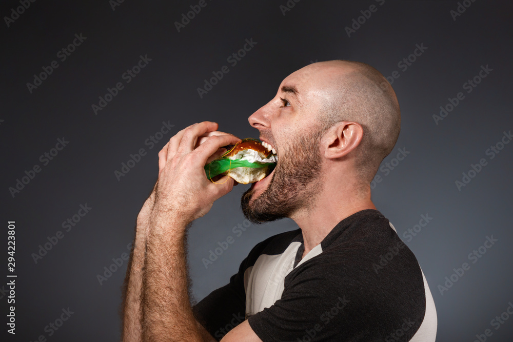 The concept of fast food and ecology. A bald man with a beard, happily ...