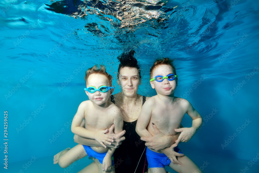 Family: a mother and two young boys swim and pose underwater in the ...