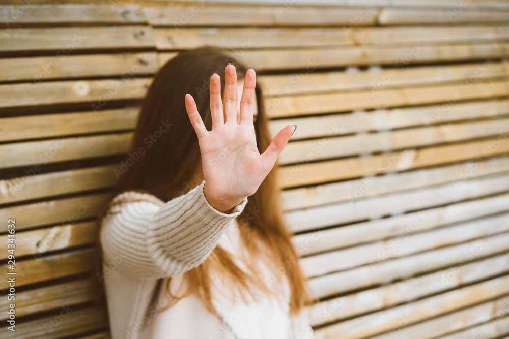 Woman with long hair reaches forward, shielding her face from camera ...