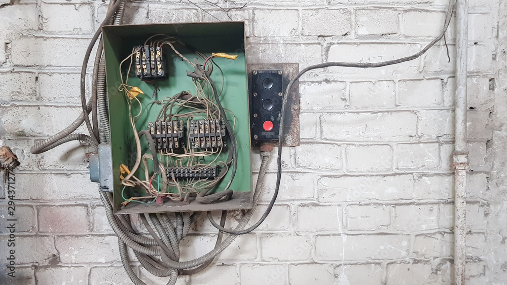 Old electrical panel on the wall of the house. Electric cables stick ...