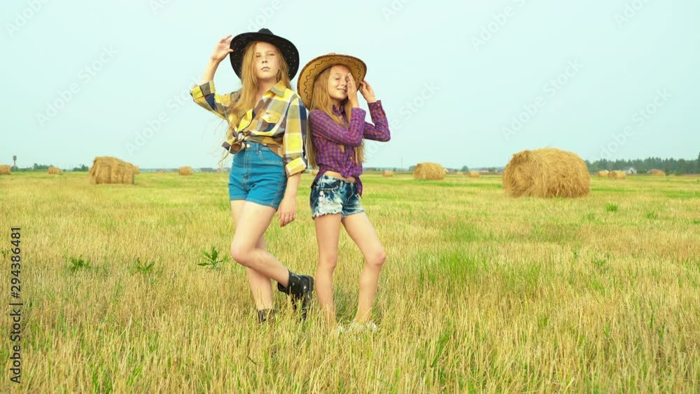 Girls in cowboy hats standing on field in countryside. Adorable teenage ...