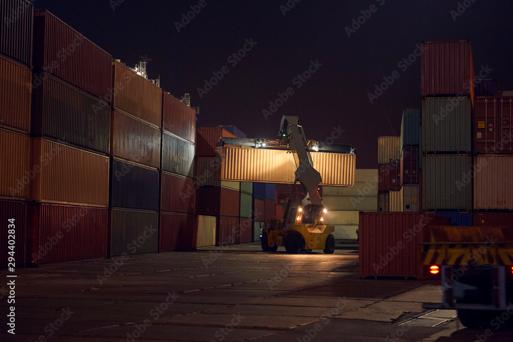 reach stacker puts container in stack. industrial port with containers ...
