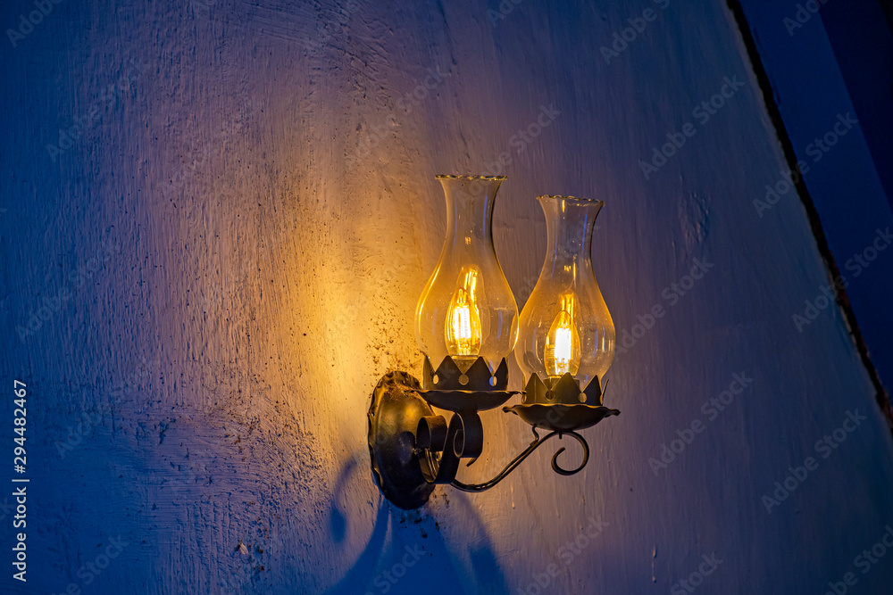 Old lamp adapted for electric light on a rustic and wrinkled wall Stock ...