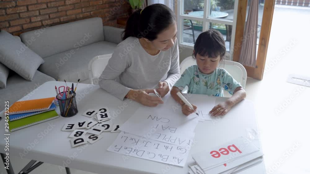mother and daughter learning to read and write letter at home together ...