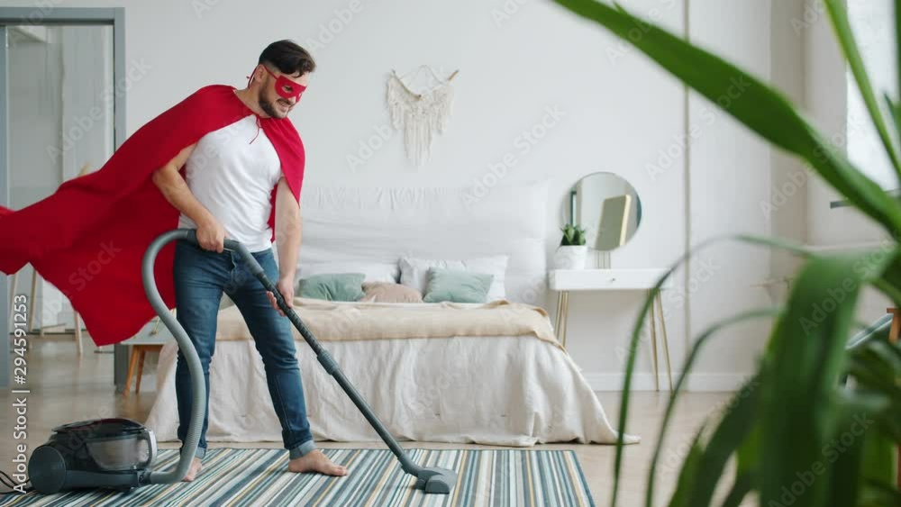 Superman in fluttering red cape and mask is standing in room with ...