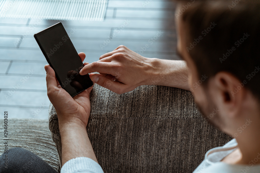 Top view of man in casual clothes tapping smartphone screen at home or ...
