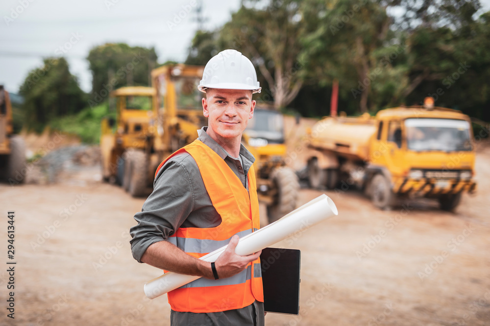 Caucasian handsome engineer is stand and smile holding a laptop with ...