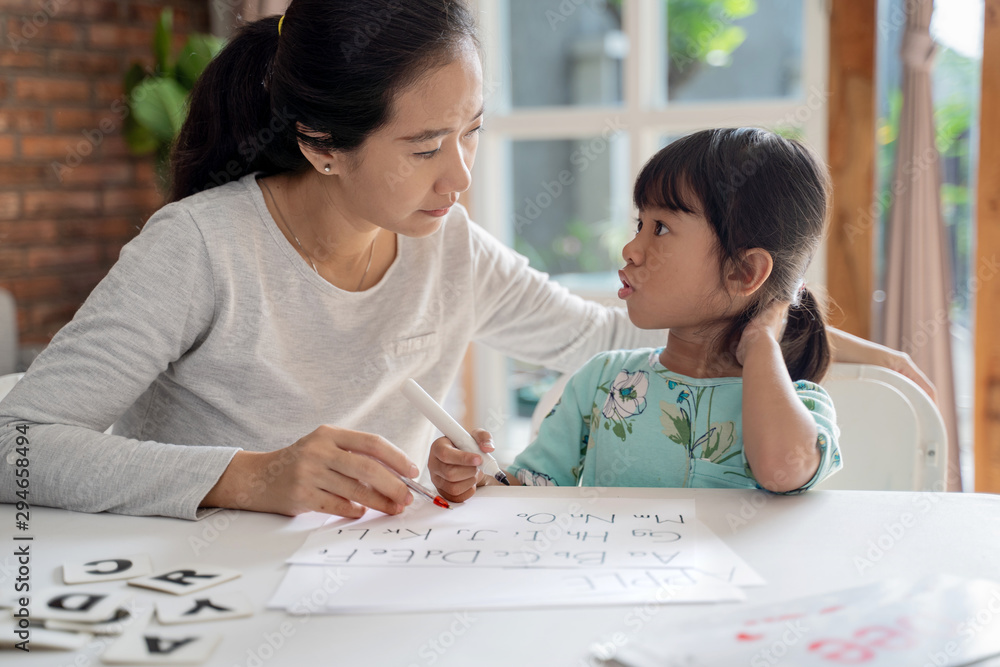 mother and daughter learning to read and write letter at home together ...
