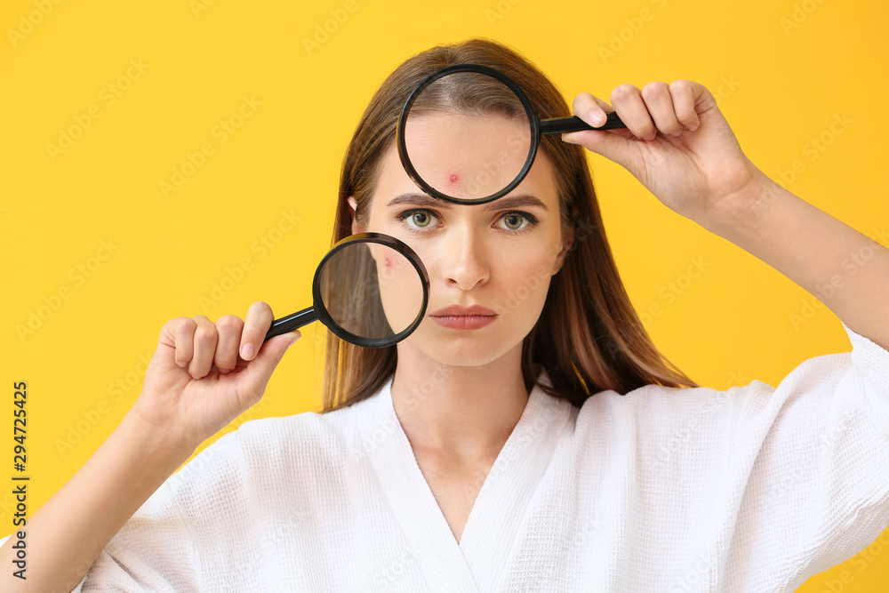 Portrait of young woman with acne problem and magnifying glasses on ...