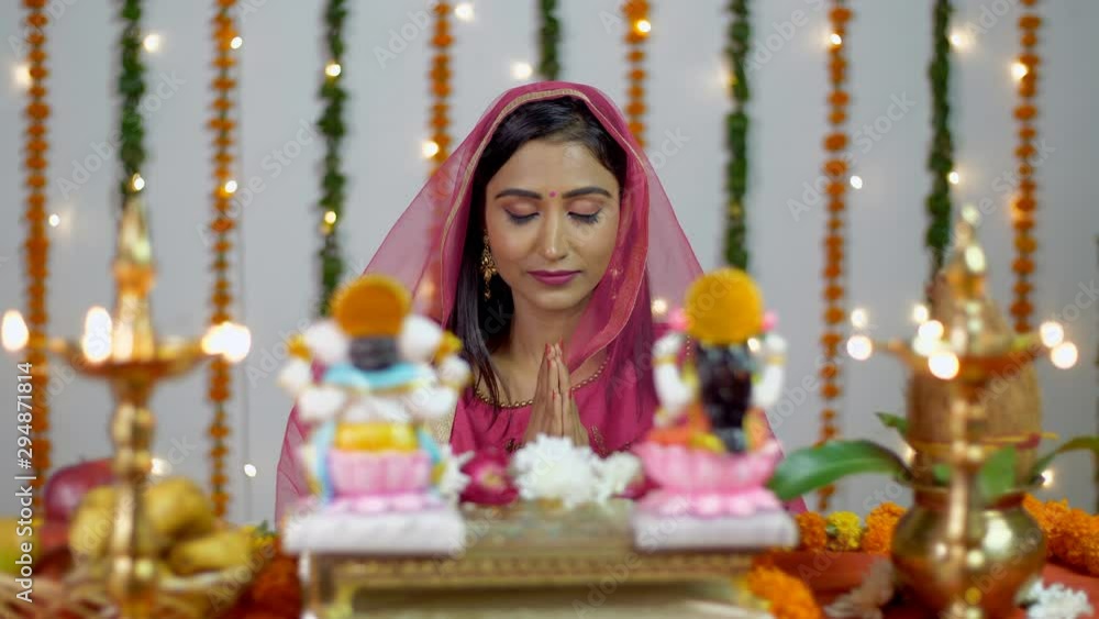 Pretty Indian female praying in front of Hindu gods Lakshmi and Ganesh ...