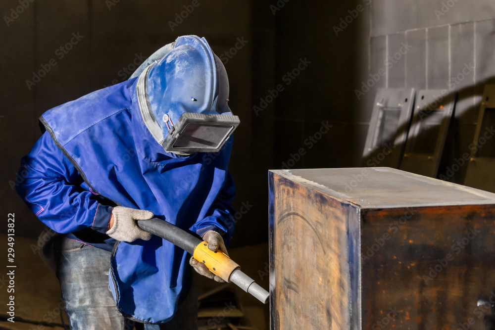 The operator of the sandblasting machine is ready to go. The worker is ...