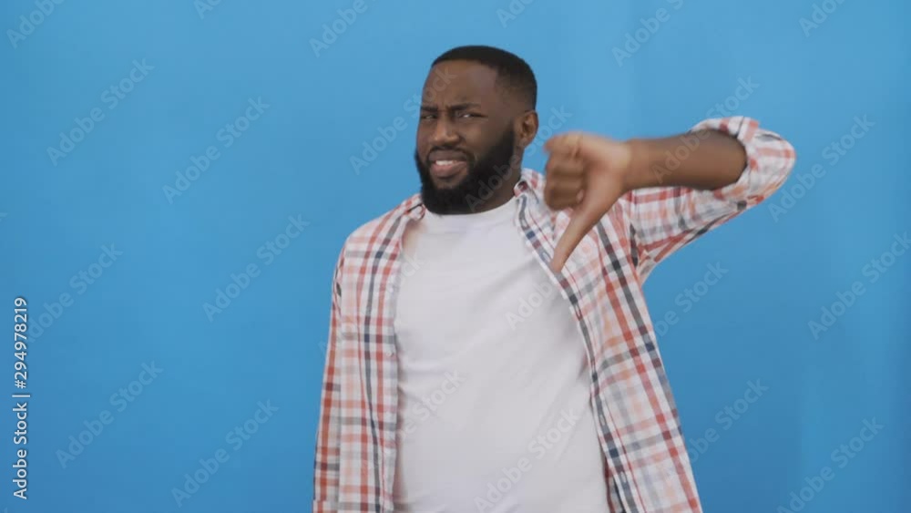 Close up emotional portrait of unhappy teen boy giving thumbs down hand ...