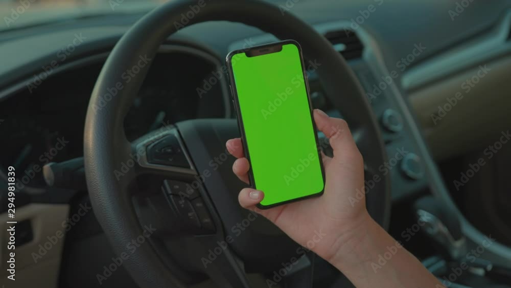Woman driver's hand showing greenscreen of vertical mock-up smartphone ...