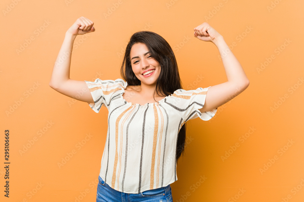 Young curvy woman showing strength gesture with arms, symbol of ...