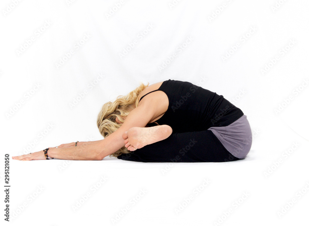 Blonde woman on white background doing seated yoga forward fold pose ...