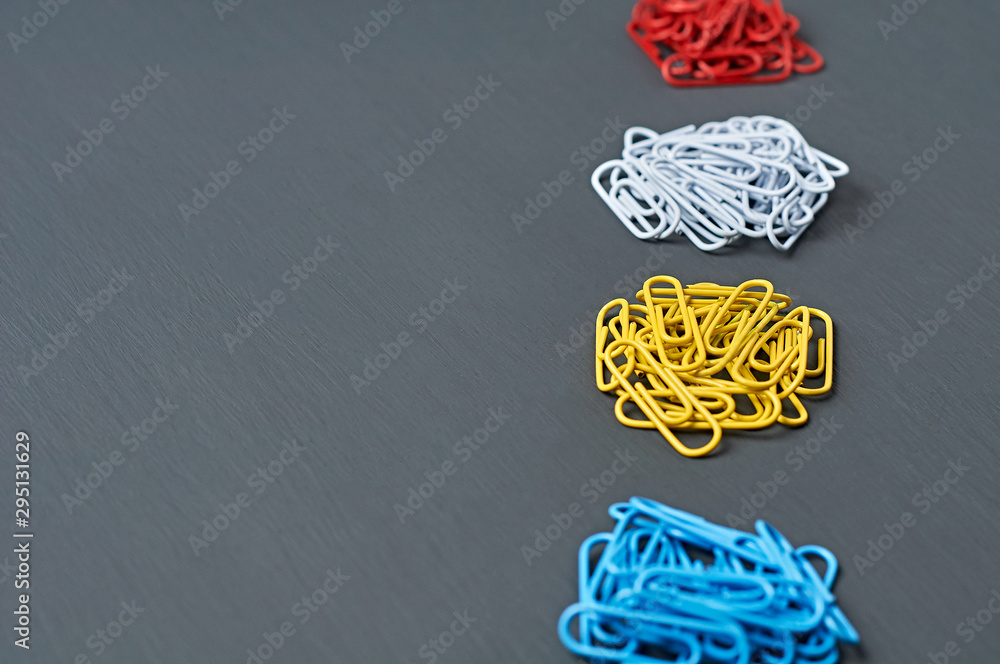 Row of four heaps of paper clips red, blue, yellow and white colors for ...