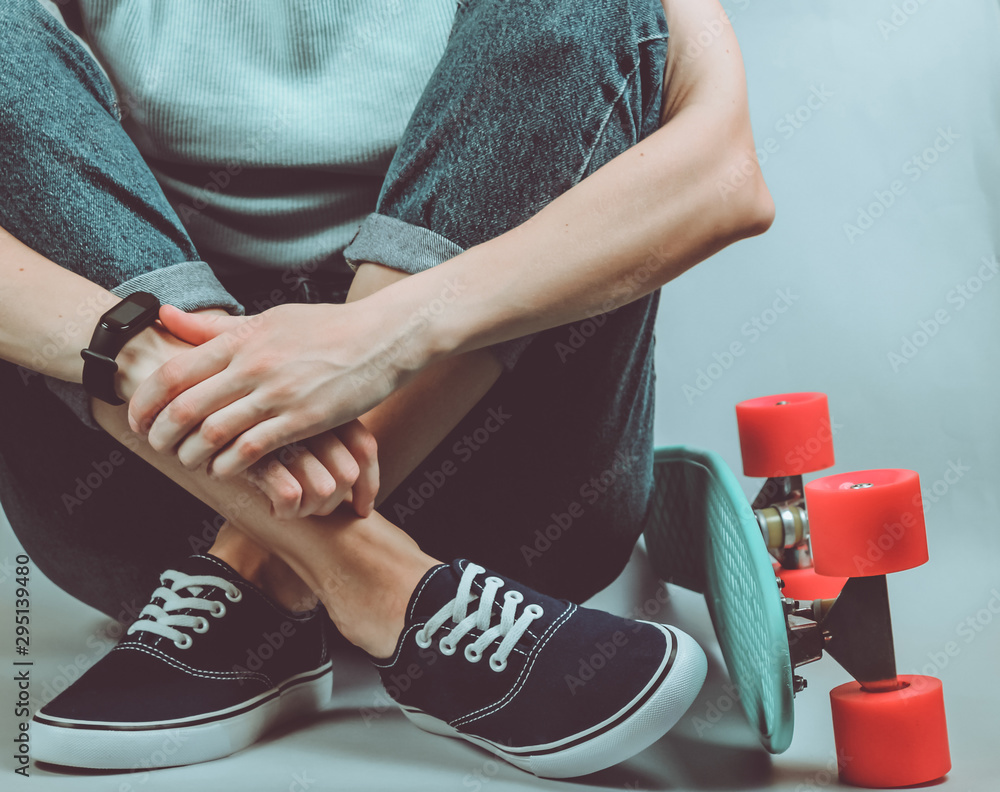 Youth hipster concept. Female legs in jeans and sneakers sitting on ...