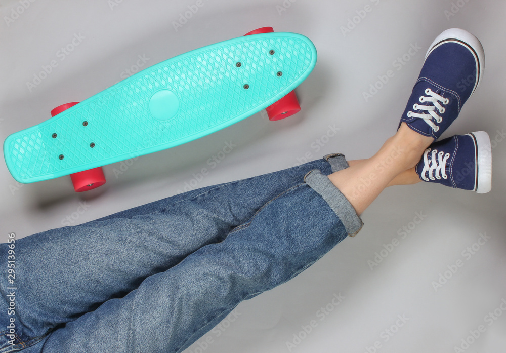Youth hipster concept. Female legs in jeans and sneakers sitting on ...