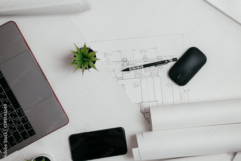 Laptop, phone and rolls of drawings on the Desk in engineering ...