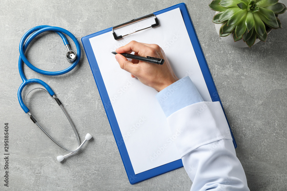 Doctor writing on grey table with stethoscope and plant, top view Stock ...