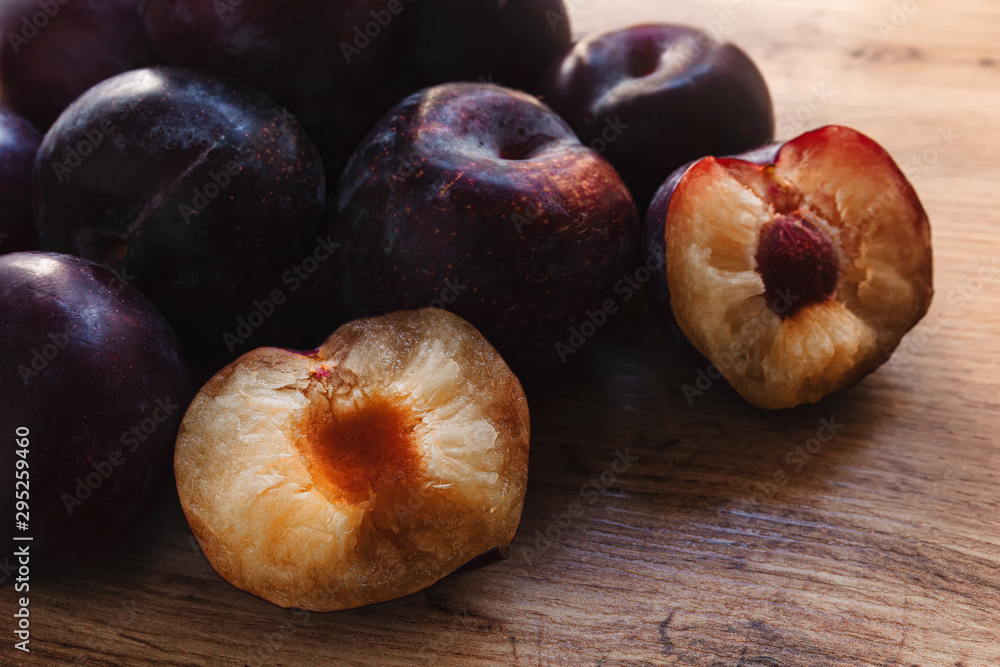 Pile of ripe plums on wooden table, with one plum torn in half Stock ...