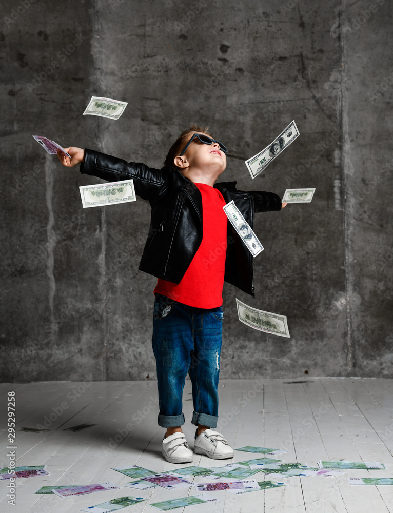 Rich kid boy in sunglasses, leather jacket and blue jeans is standing ...