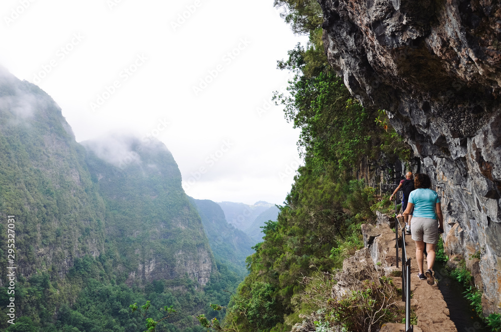 Foto de Tourists hiking on a narrow path on the edge of the rock during ...