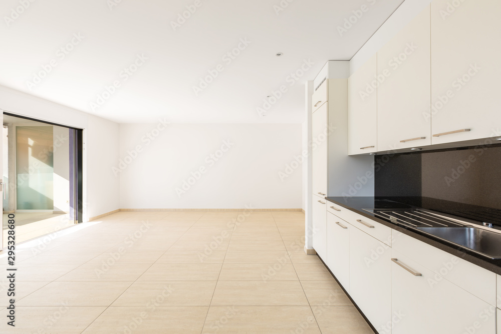 Empty room with white walls, travertine floor and white kitchen and ...