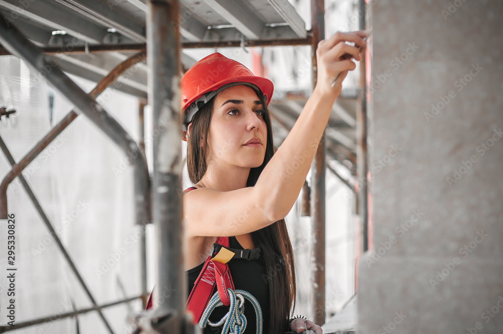 Female construction mason on the scaffolding, plastering and renovating ...