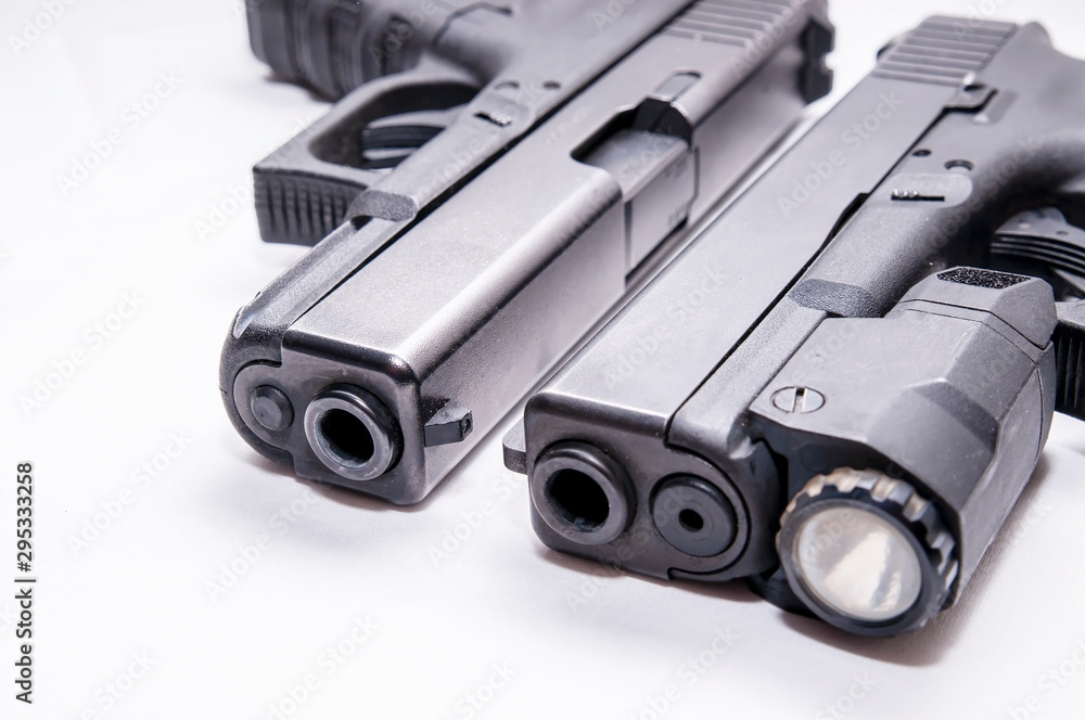 Two black semi automatic 9mm pistols, one with a flashlight attached ...